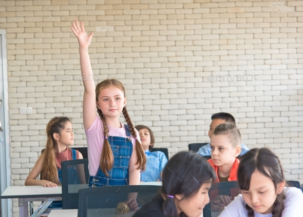 Elementary school female students stand and raise their hands to ask class teacher Stock Photo ...