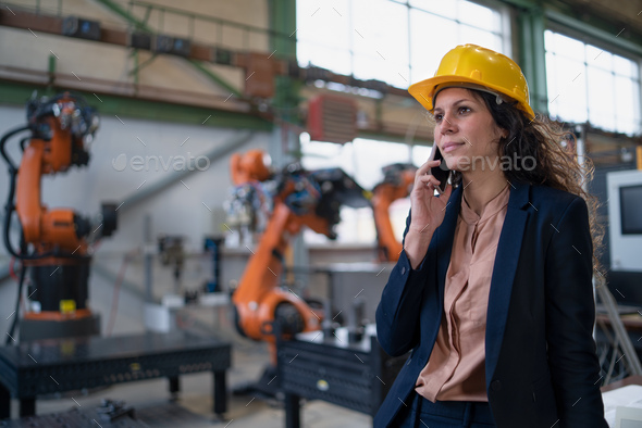 Automation female engineer with tablet for programming robotic arm calling on cellphone and ...