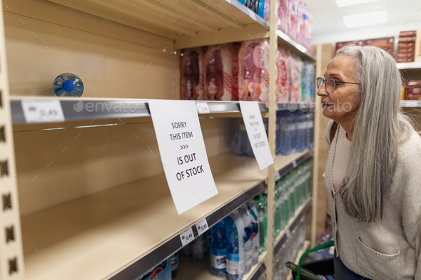 Depressed senior woman shopper in front of empty shelves in a grocery ...