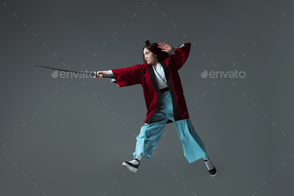 full length view of samurai in kimono fighting with katana in jump ...