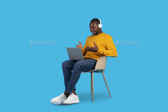 Cheerful black man using laptop and wireless headphones, telecommunication concept Stock Photo ...
