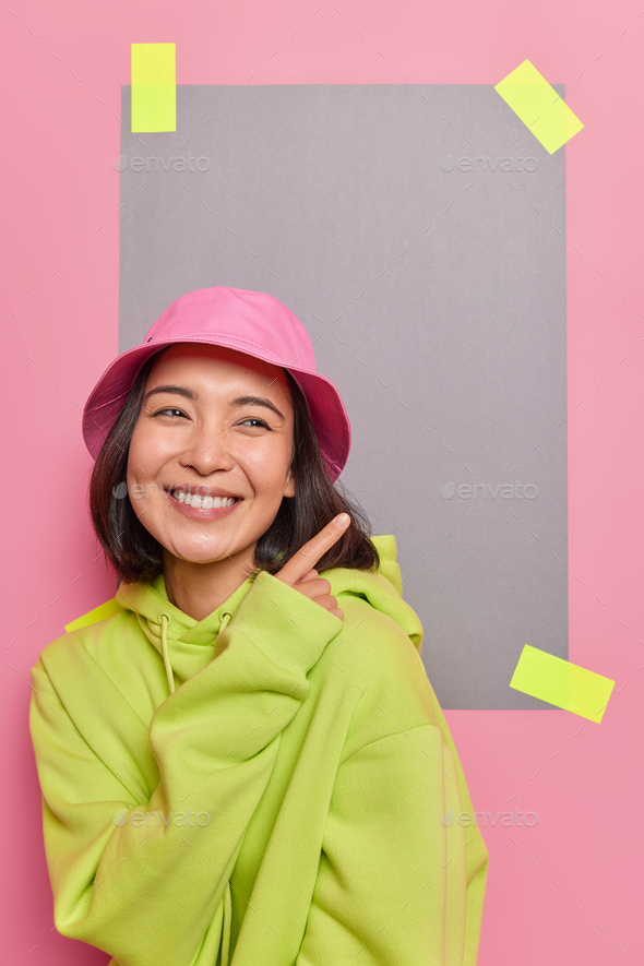 Happy Asian girl indicates at empty space for sale logo smiles ...