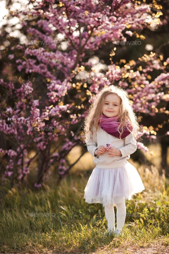 Pretty little child girl 4-5 year old with flowers over blooming nature ...