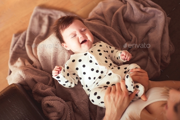 Crying baby on mother hands in room. Motherhood. Stomach ache. Stock ...