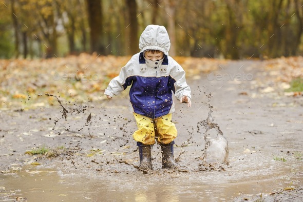 Jumping in the muddy puddles. Fun kids activities Stock Photo by Portoprens