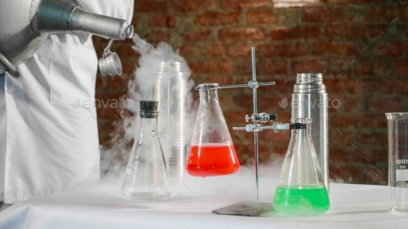Scientist pouring liquid nitrogen in steel thermos bottle at laboratory ...