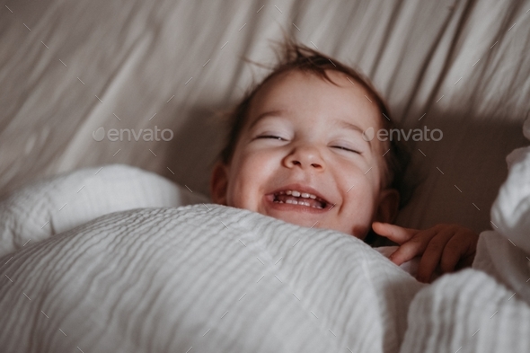 Infant girl portrait in bed after sleeping time in neutral cozy colours ...