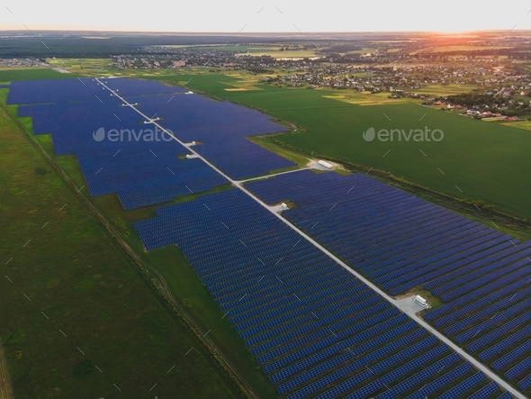 Aerial drone view into large solar panels at a solar farm at bright ...