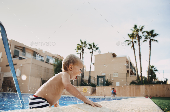 Little baby boy getting out from the swimming pool with drops of water ...