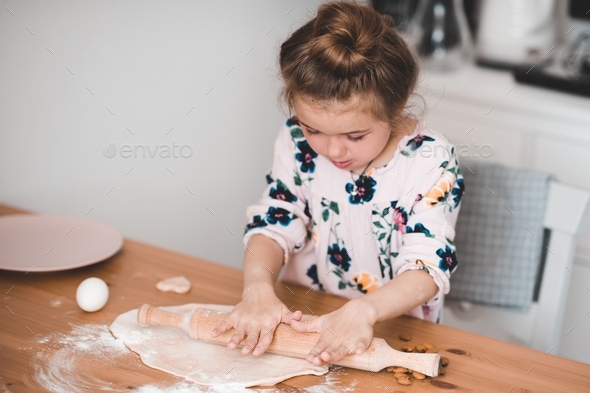 Smiling kid girl 4-5 year old making cake in kitchen. Cooking child in ...