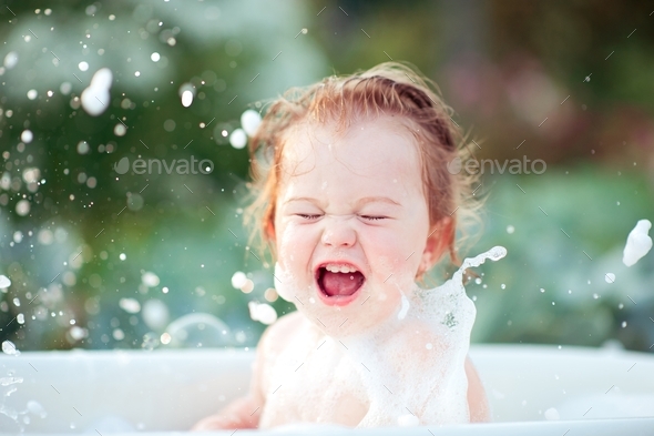 Smiling baby girl washing in bath outdoors. Laughing child. Childhood ...