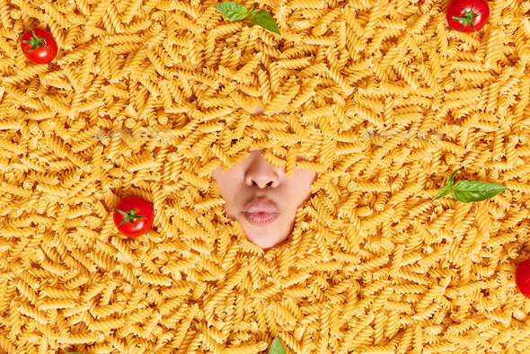 Unrecognizable human face covered with italian pasta tomatoes and basil ...