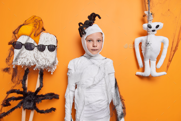 Scared small female child enjoys halloween celebrations with theme of ...