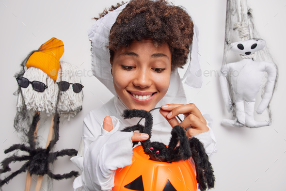 Pleased cheerful young woman plays with spider touches its legs holds ...