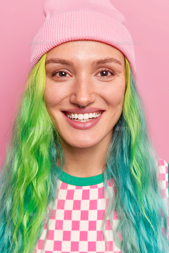 Vertical shot of pleased cheerful hipster girl smiles broadly shows ...