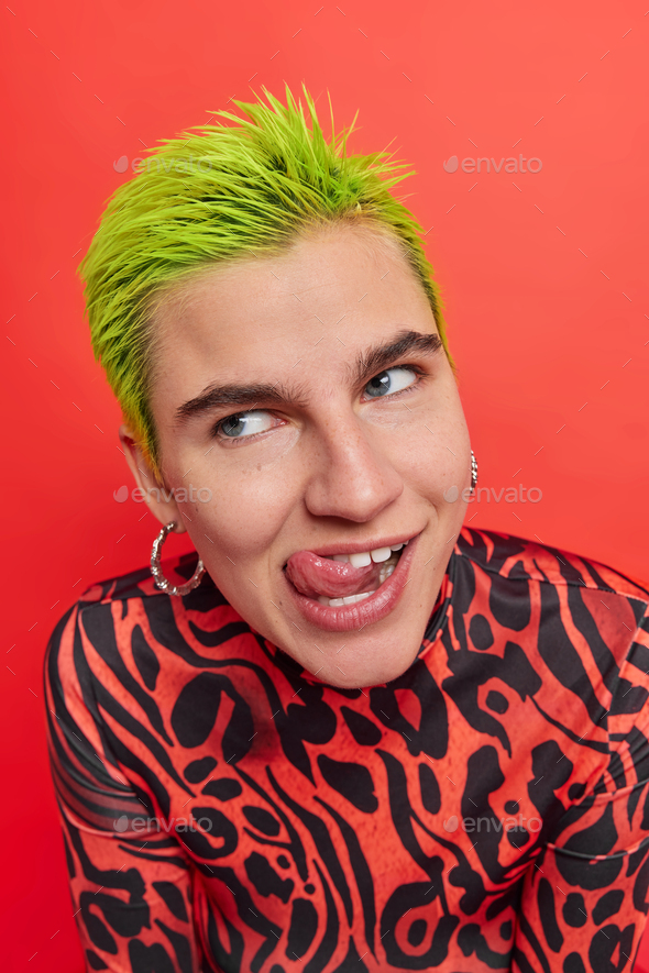 Dreamy stylish female rock fan licks lips with tongue looks at ...