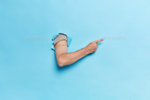 Unrecognizable human breaks arm through paper background wears adhesive ...