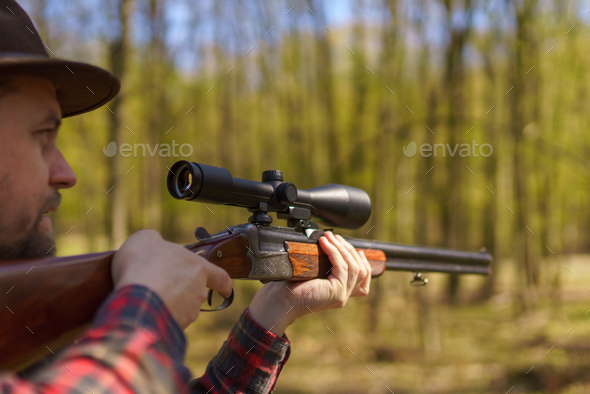 Hunter man aiming with rifle gun on prey in forest. Stock Photo by ...