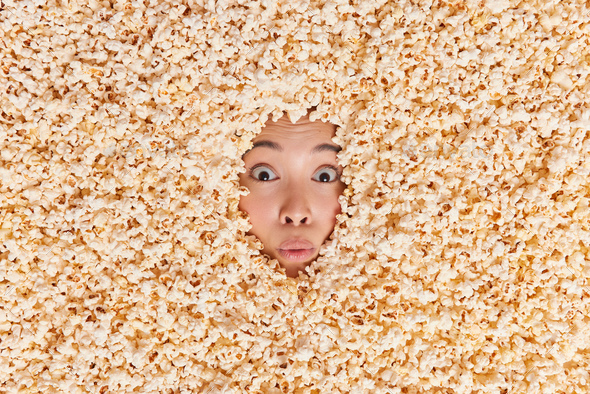 Image of astonished woman showing only face poses against popcorn ...