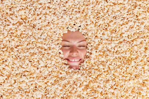 Overhead shot of cheerful woman shows white teeth buried in delicious ...