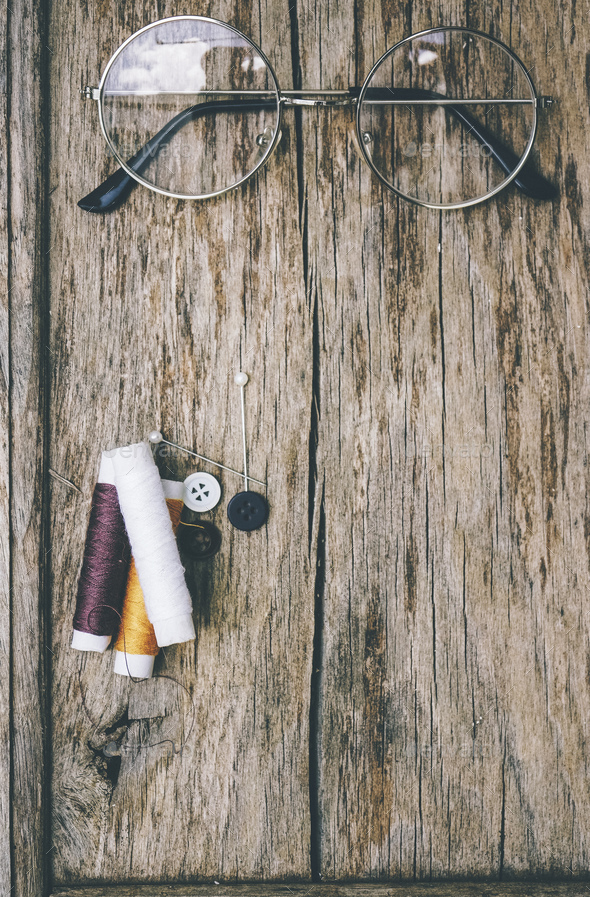 Sewing theme background with brown tones thread and a vintage glasses ...