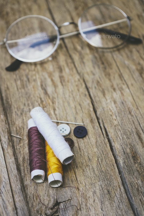 Sewing theme background with brown tones thread and a vintage glasses ...
