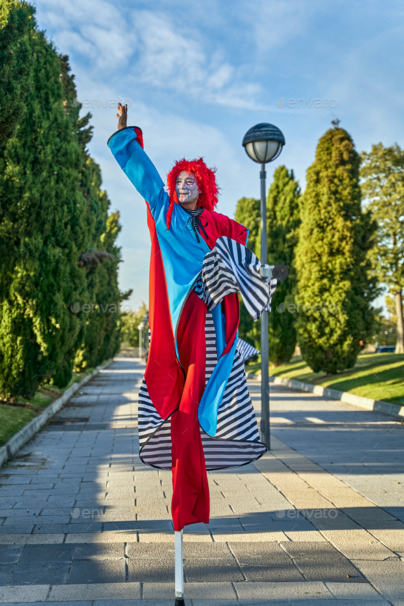 Creative clowns on stilts walking on pathway in sunny park Stock Photo ...