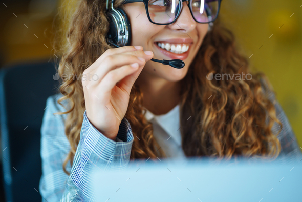 Call center agent with headset working on support hotline in modern office. Video conference ...