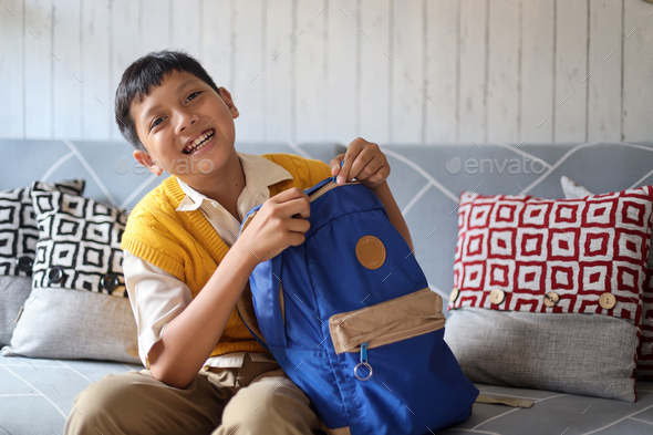 Smiling schoolboy preparing backpack for school Stock Photo by ...