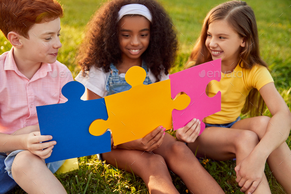 Smiling diverse kids playing with colorful puzzle Stock Photo by kegfire