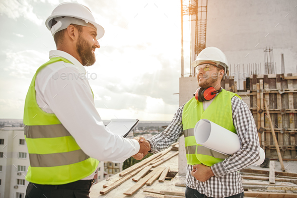 Positive construction workers shaking hands Stock Photo by kegfire