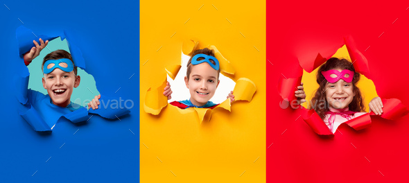 Positive superhero kids looking through torn paper Stock Photo by kegfire