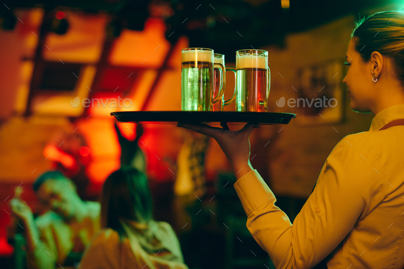 Young waitress serving beer while working in a bar at night. Stock ...