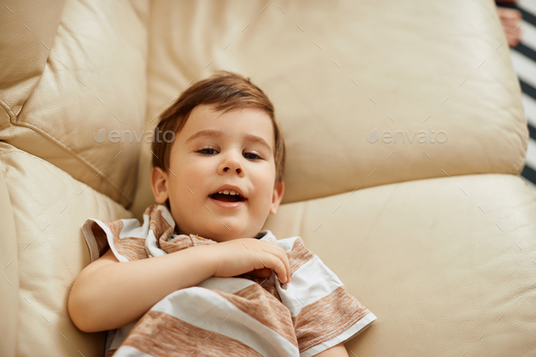 Cute little boy relaxing on the sofa and looking at camera. Stock Photo ...