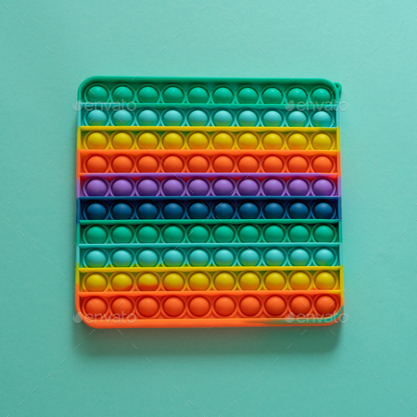 Bright silicone striped toy big Pop It closeup on blue background ...