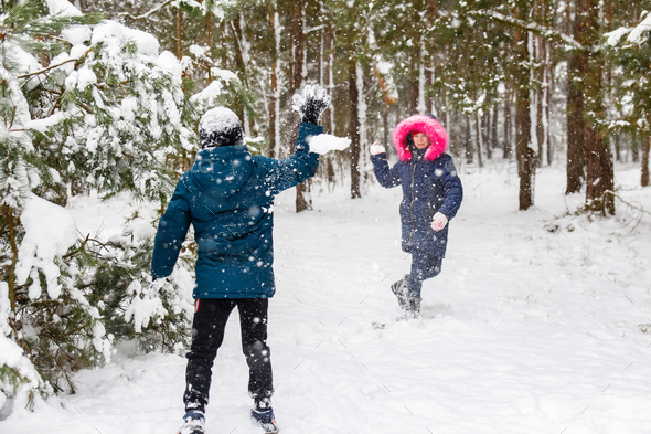 boy swinging a snowball with a girl. Funny children in Winter Park ...