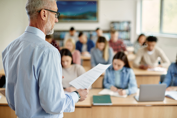 Mature university professor giving lecture to his students in the ...