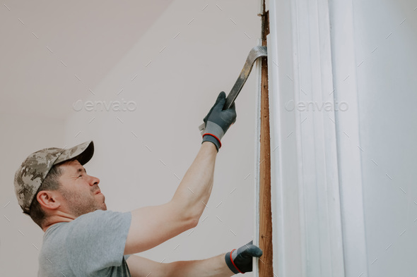 Hands of a man working with a crowbar indoors. Stock Photo by NataKor5