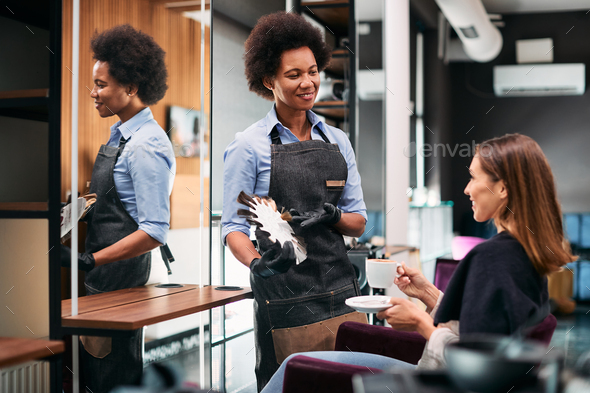 Happy African American hairdresser showing hair color palette to her ...