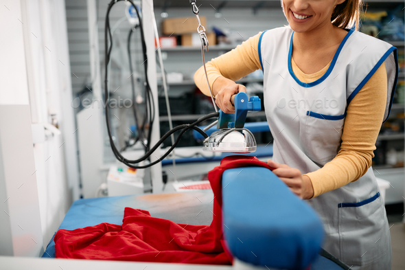 Unrecognizable woman ironing textile while working at clothing factory ...