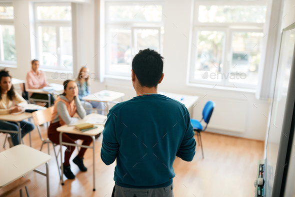 Rear view of teacher giving lecture to high school students in the ...