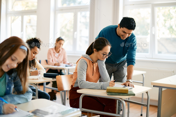 Female high school student leaning with teacher's help in the classroom ...