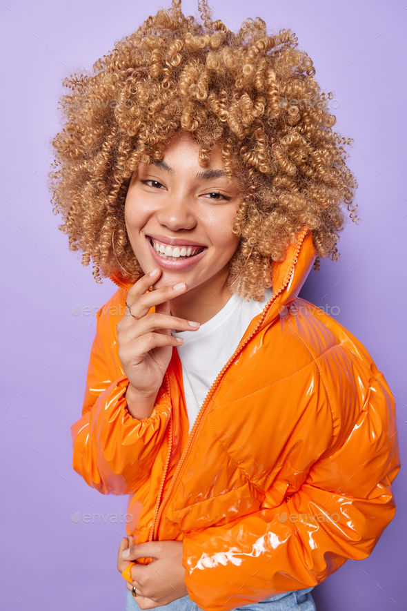 Photo of positive good looking woman with curly bushy hair keeps hand ...