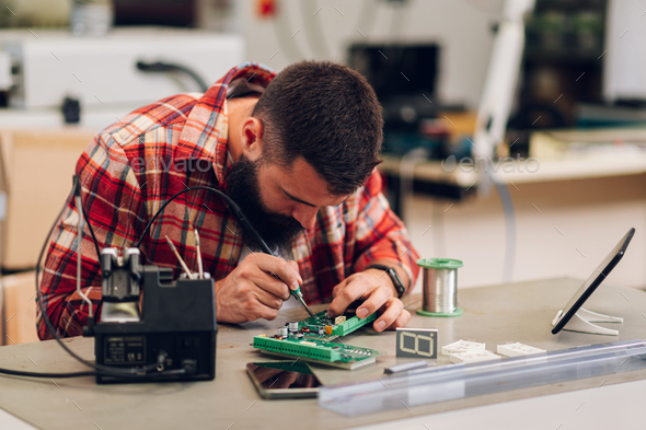 Electronics engineer working in a workshop with tin soldering parts ...