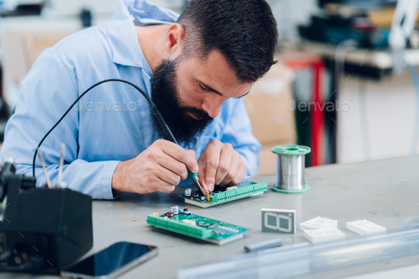 Electronics engineer working in a workshop with tin soldering parts ...