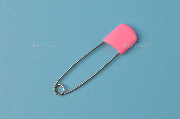 Pink safety pin isolated on a blue background Stock Photo by innu_asha84