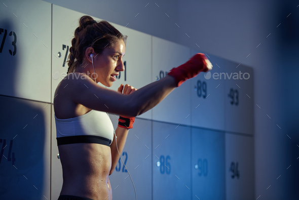 Female athlete in fighting stance warming up in locker room before ...