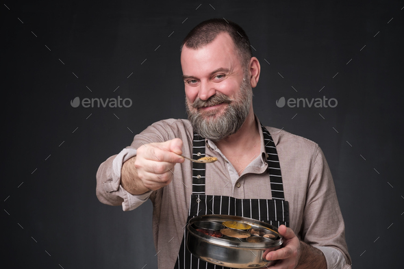 Bearded male chef showing different spices he uses. Secret of delicious ...