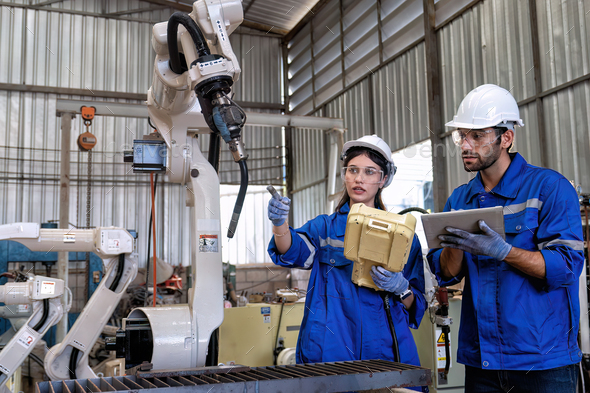 In robotic training center instructor use tablet pc teach girl engineer how to program robot arm ...