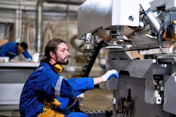 In wooden industrial engineer stand at circular saw machine controller ...